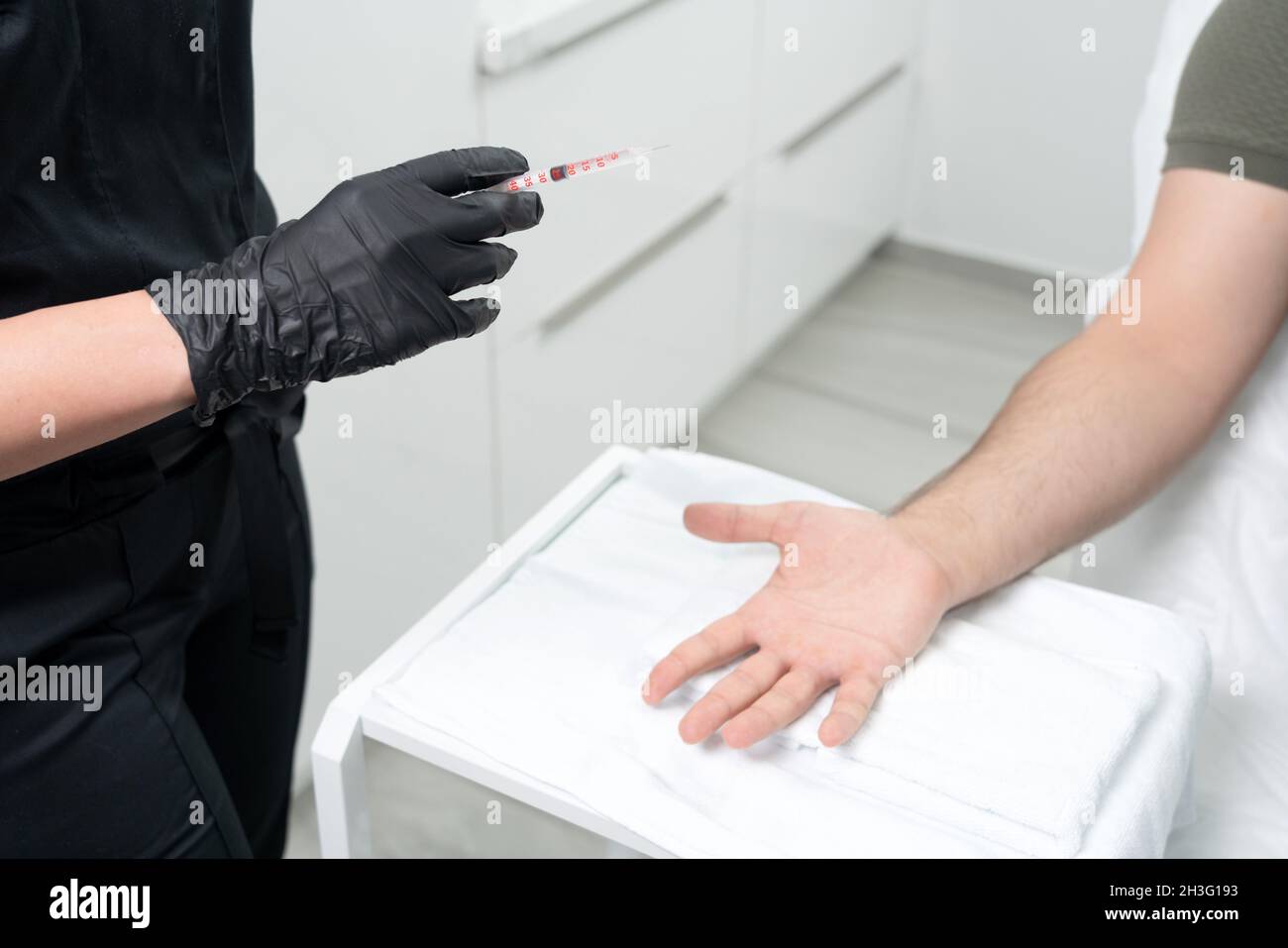 doctor makes a shot of botulinum toxin in the hand of a male palm ...