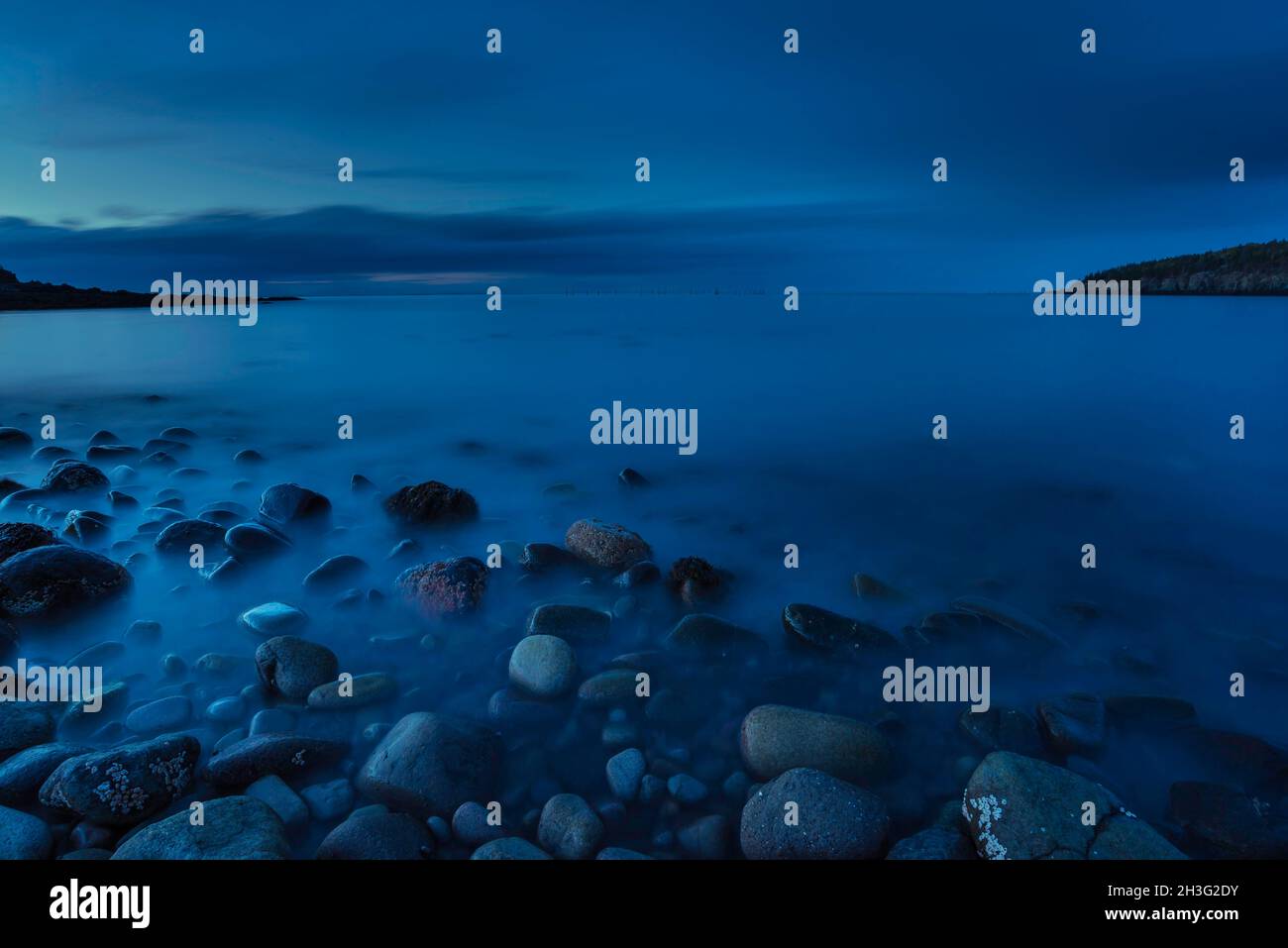 Very long exposure during blue hour after sunset on rocky seashore of ...