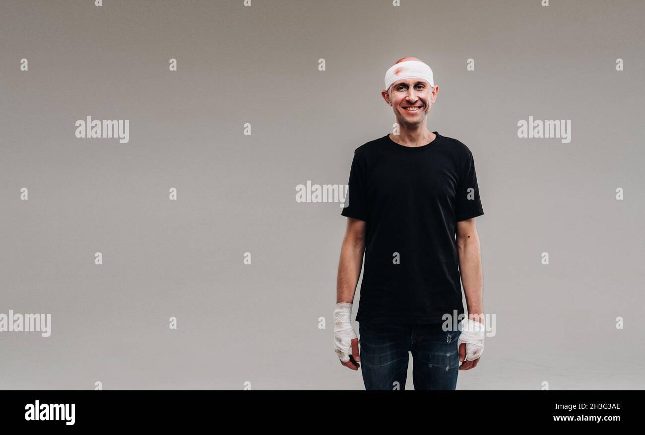 Against a gray background stands a battered and battered man in a black ...