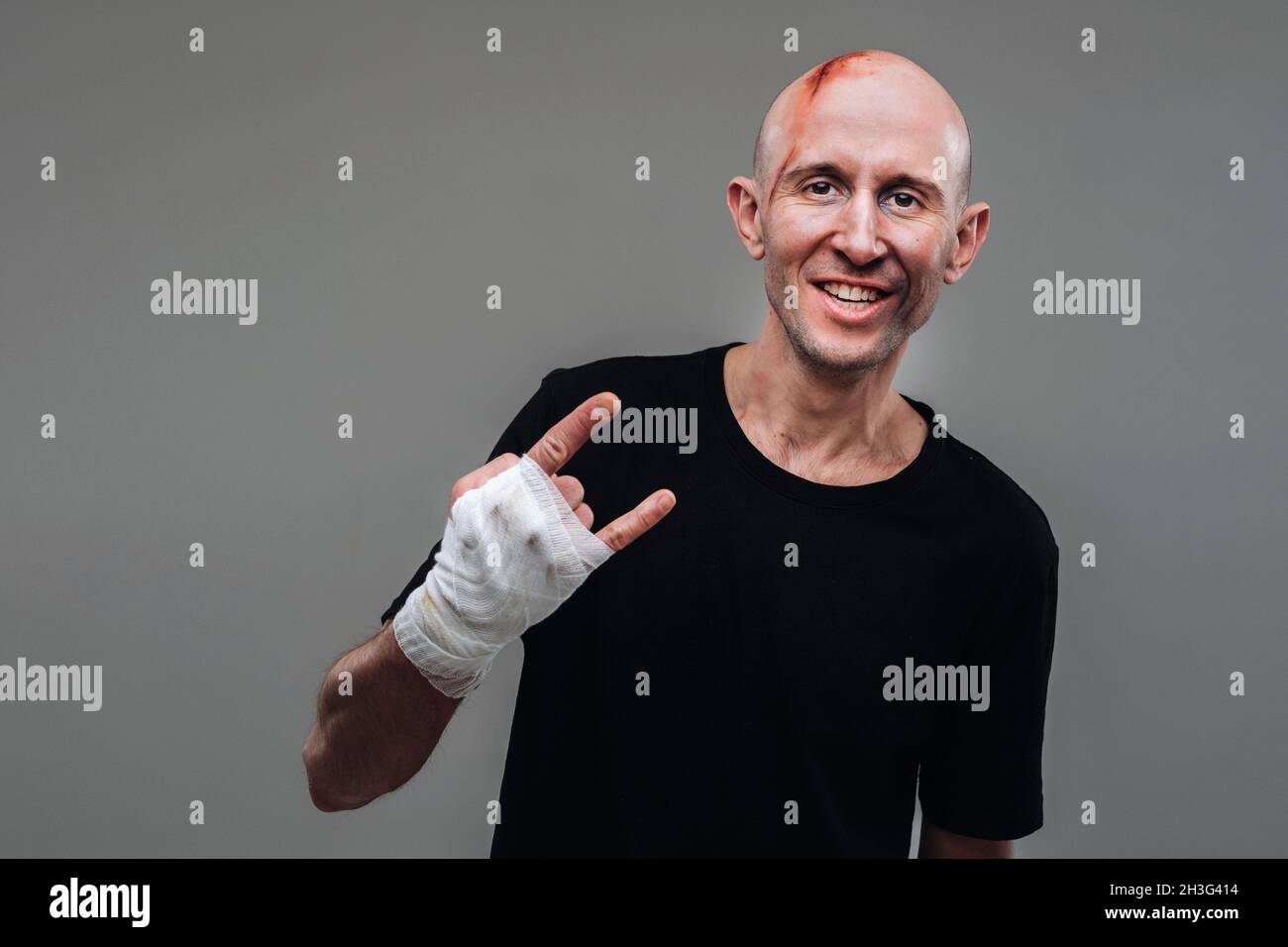 On a gray background stands a battered man in a black T-shirt With his ...