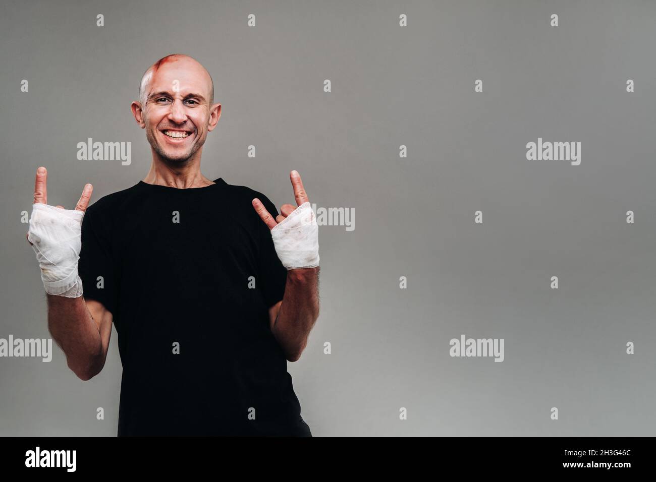a battered man with his hands wrapped in a black T-shirt on a gray ...