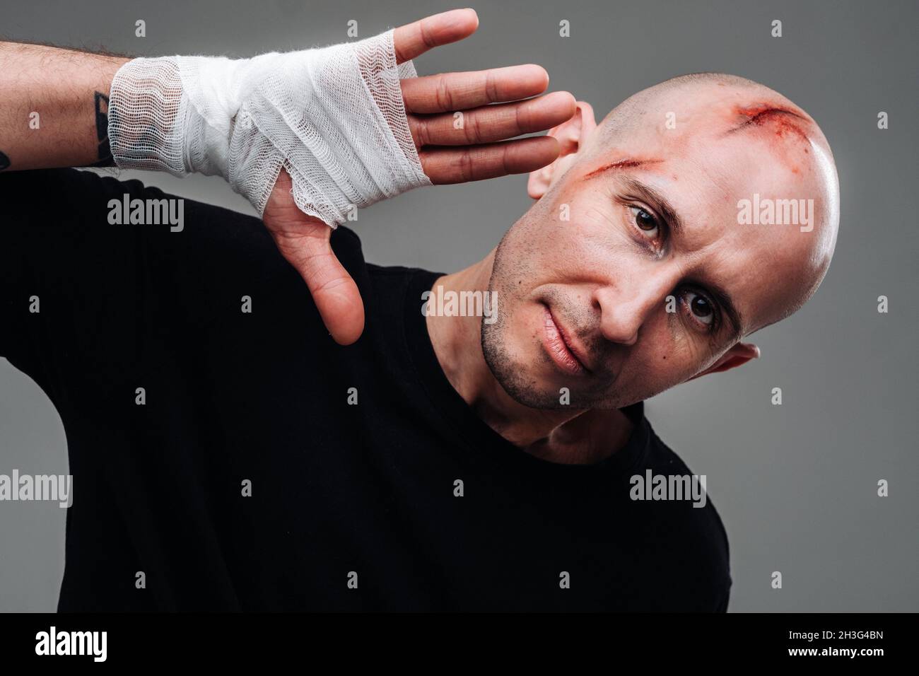 On a gray background stands a battered man in a black T-shirt With his ...