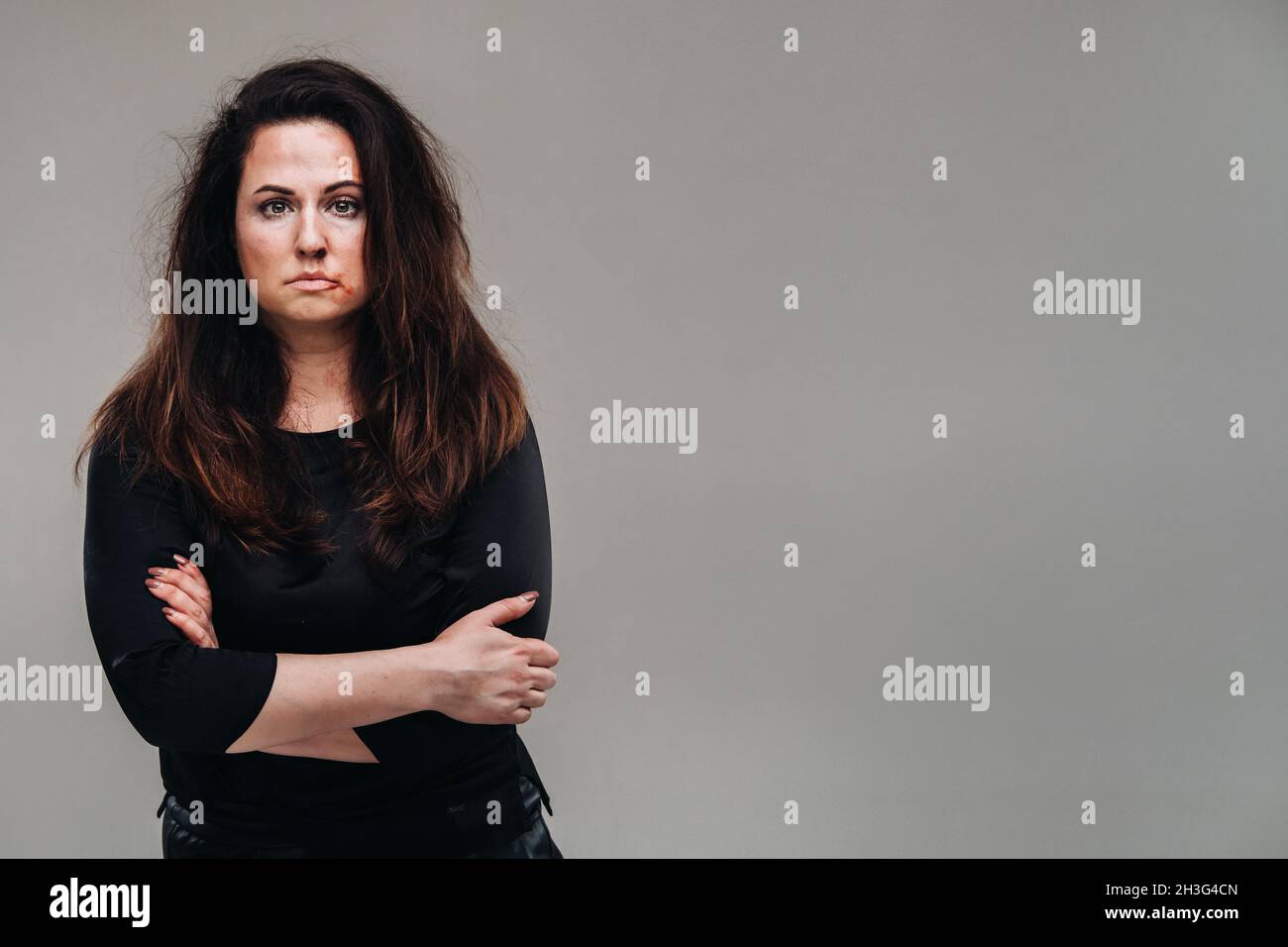 a battered woman in black clothes on an isolated gray background ...