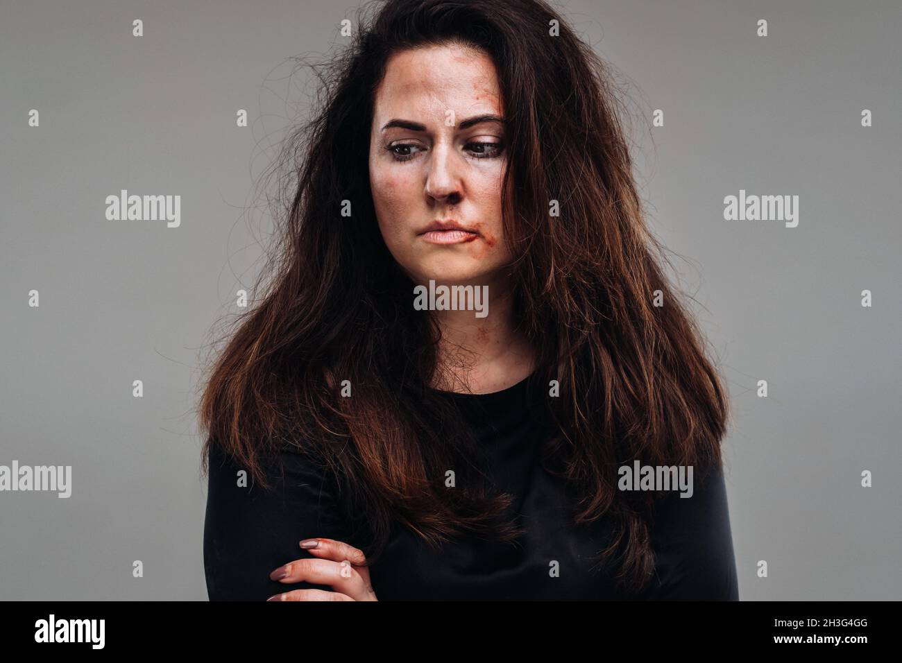 a battered woman in black clothes on an isolated gray background ...