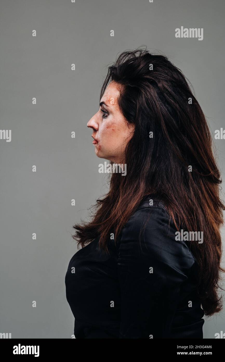 a battered woman in black clothes on an isolated gray background ...