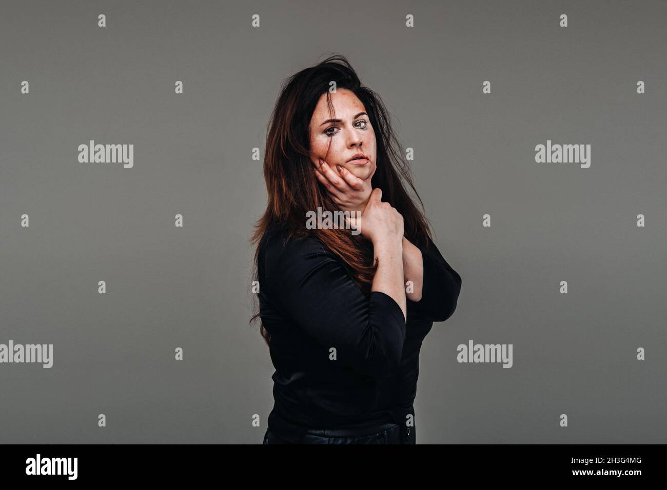 a battered woman in black clothes on an isolated gray background ...