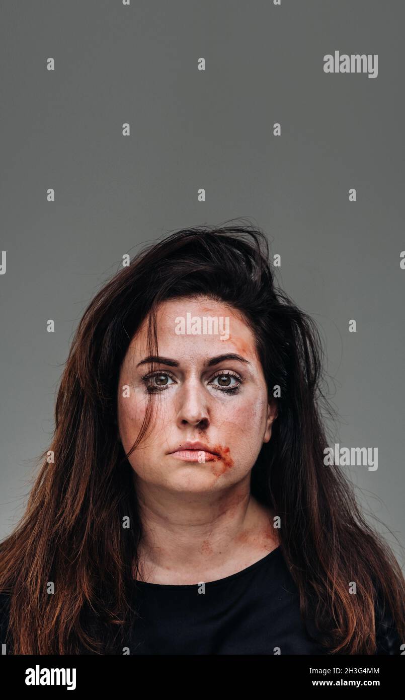 a battered woman in black clothes on an isolated gray background ...