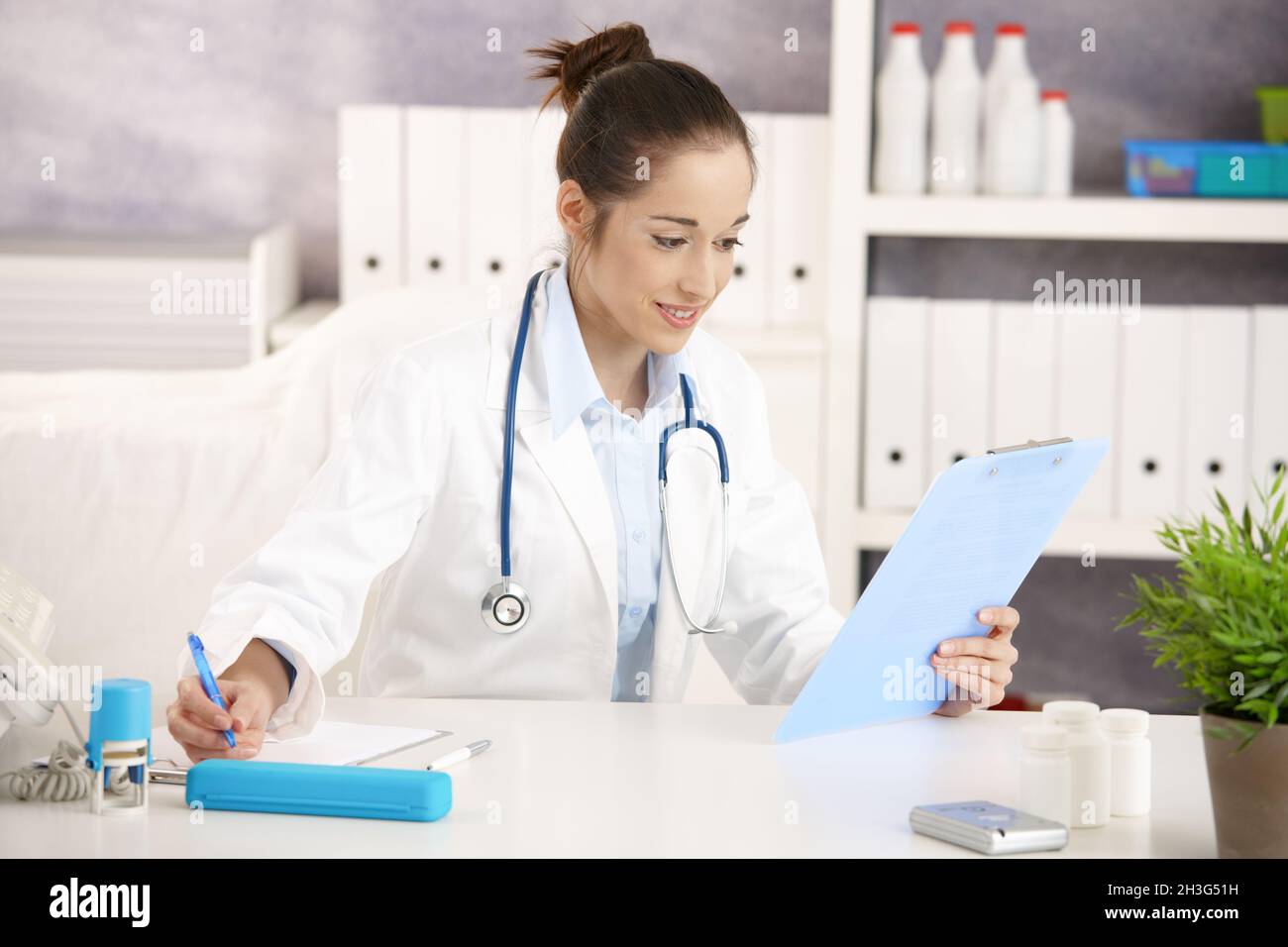 Doctor doing paperwork at office Stock Photo - Alamy