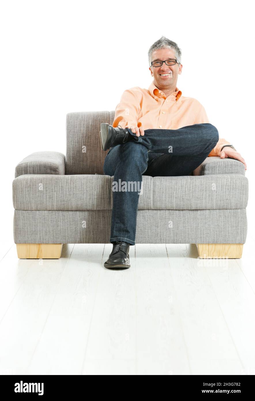 Happy man sitting on couch Stock Photo - Alamy