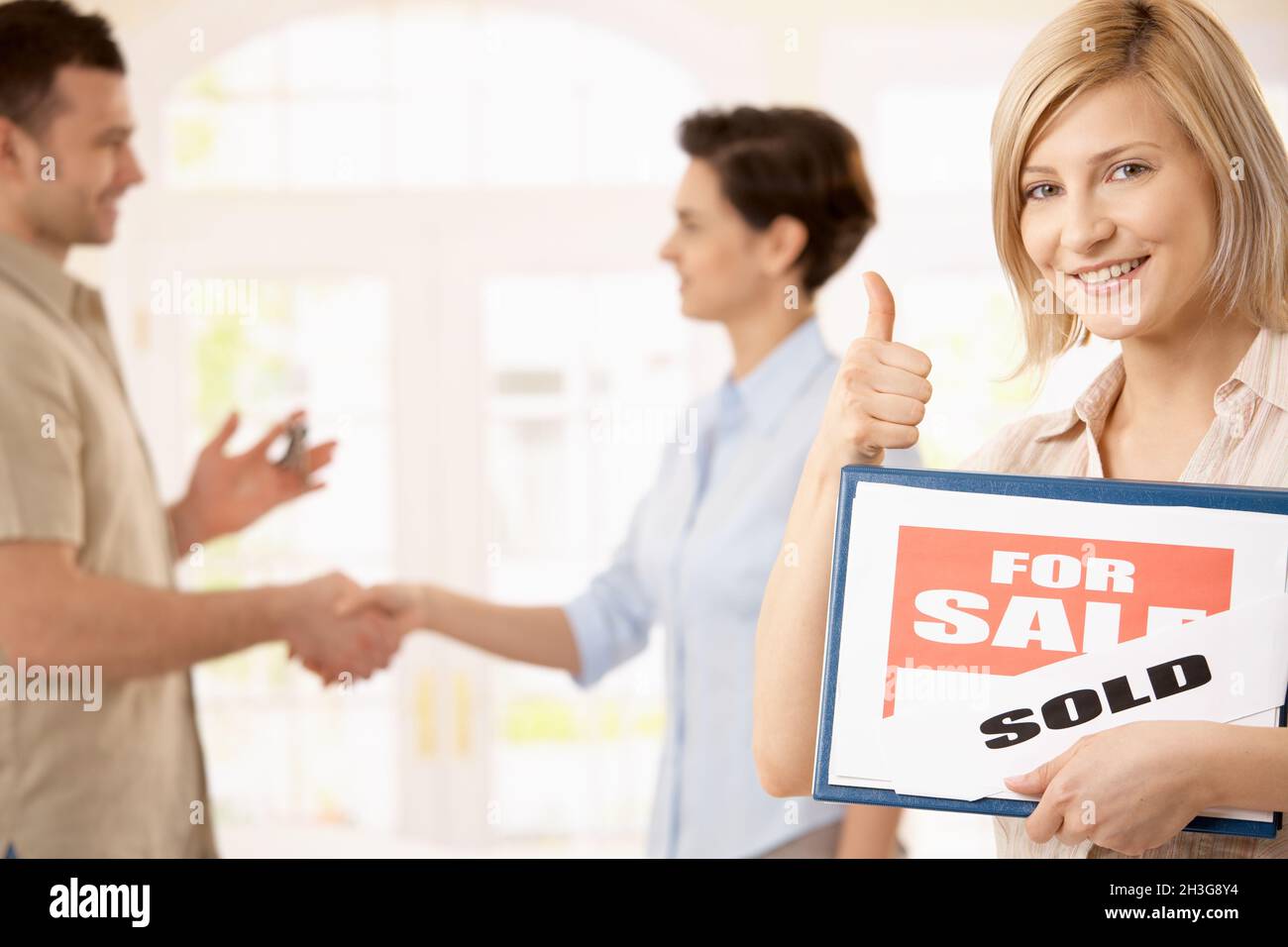 Happy woman with for sale sign Stock Photo - Alamy