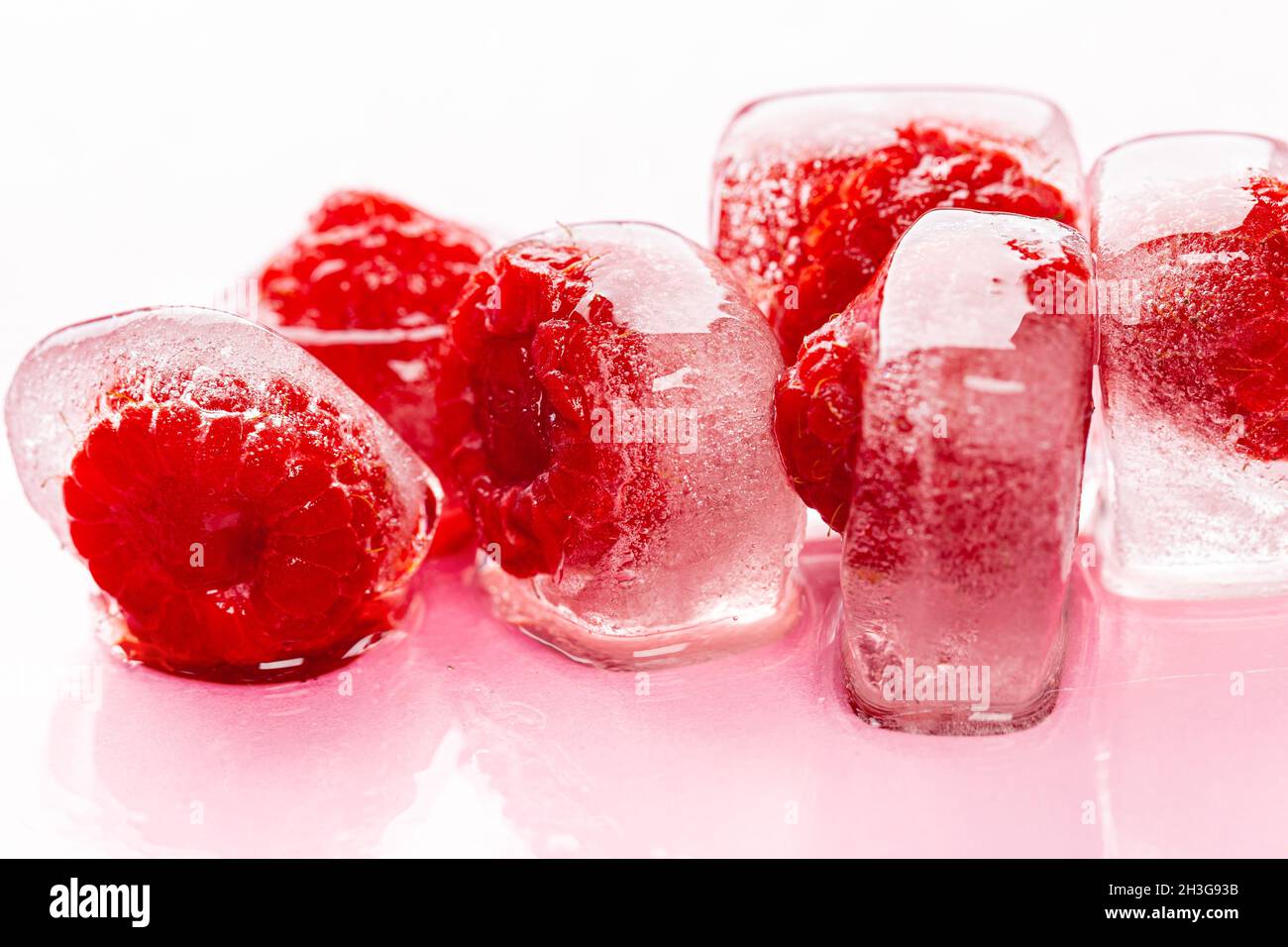 Raspberry ice cubes on pink glossy background Stock Photo - Alamy