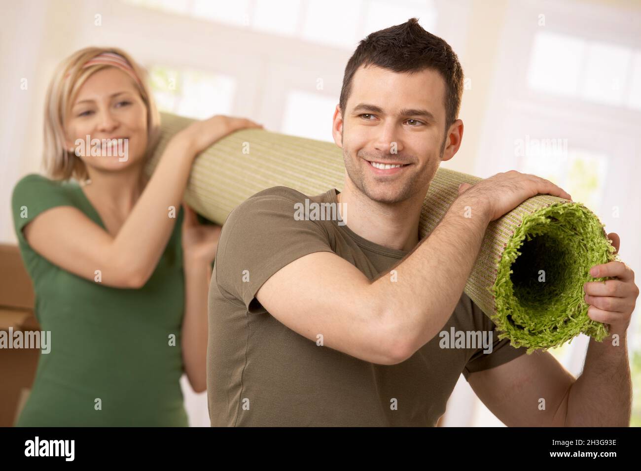 Happy couple carrying carpet together Stock Photo - Alamy