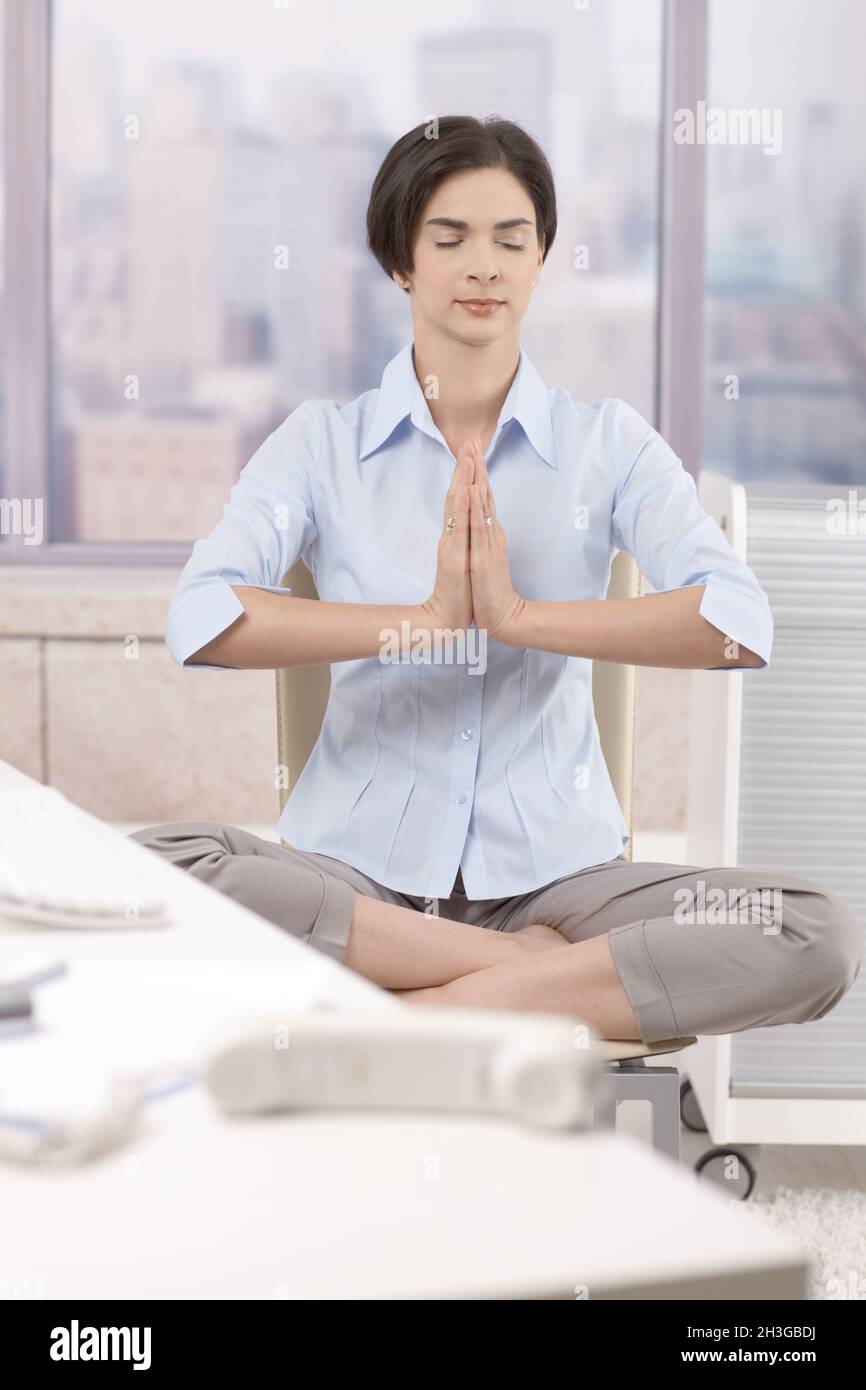Female office worker meditating at work Stock Photo - Alamy