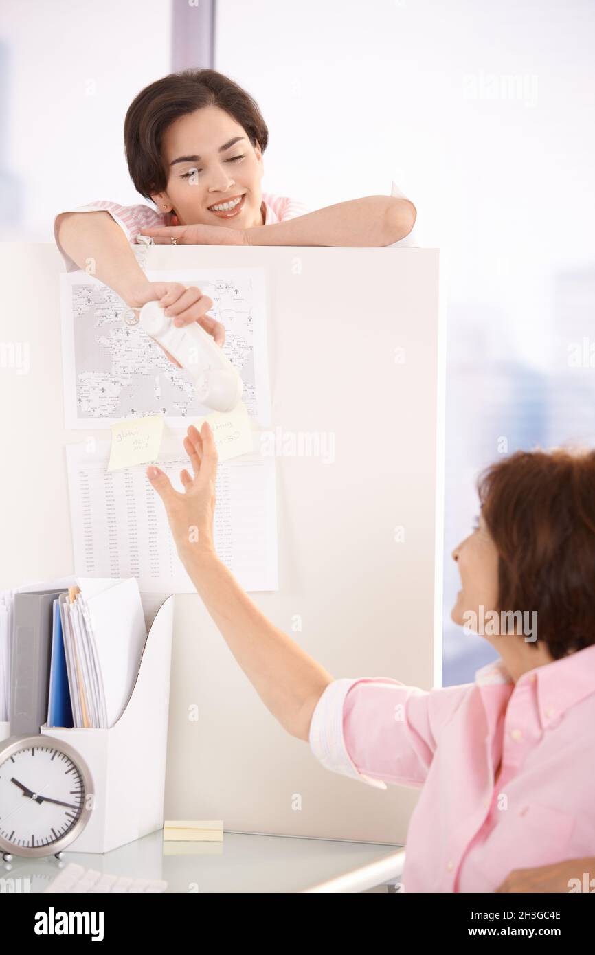 Colleague handing over phone to office worker Stock Photo - Alamy