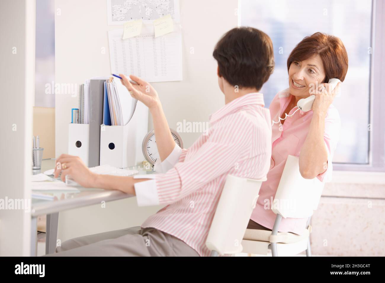 Female office workers sitting at desk Stock Photo - Alamy