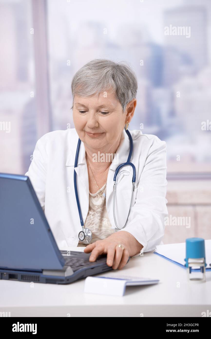 Senior doctor using laptop computer Stock Photo - Alamy