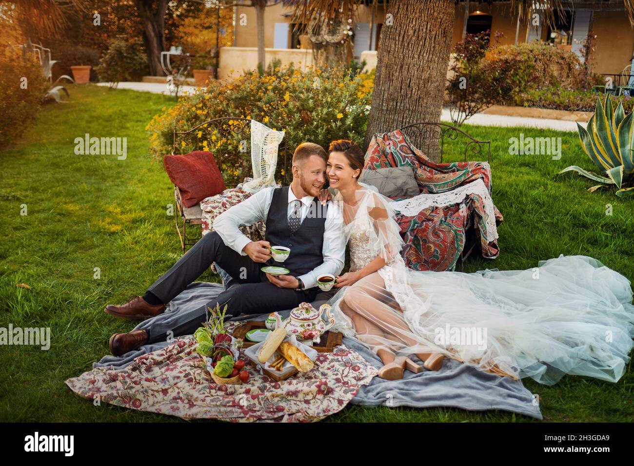 Newlyweds ' dinner on the lawn at sunset.A couple sits and drinks tea ...