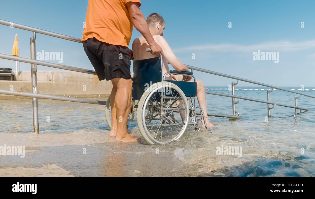 Man with disability on a wheelchair being transported into sea for ...