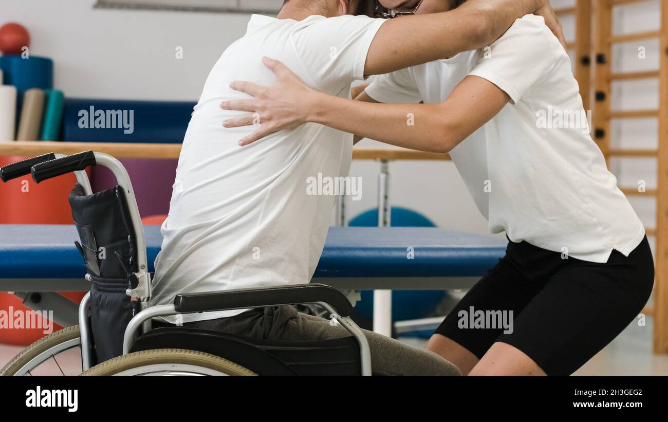 Person with disability and female physiotherapist, exercise standing up ...