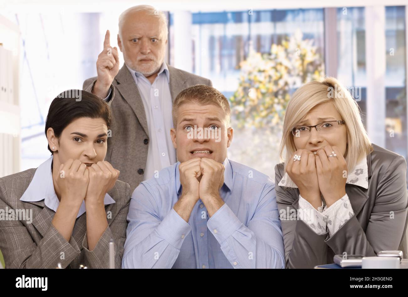 Scared employees sitting with angry boss behind Stock Photo - Alamy