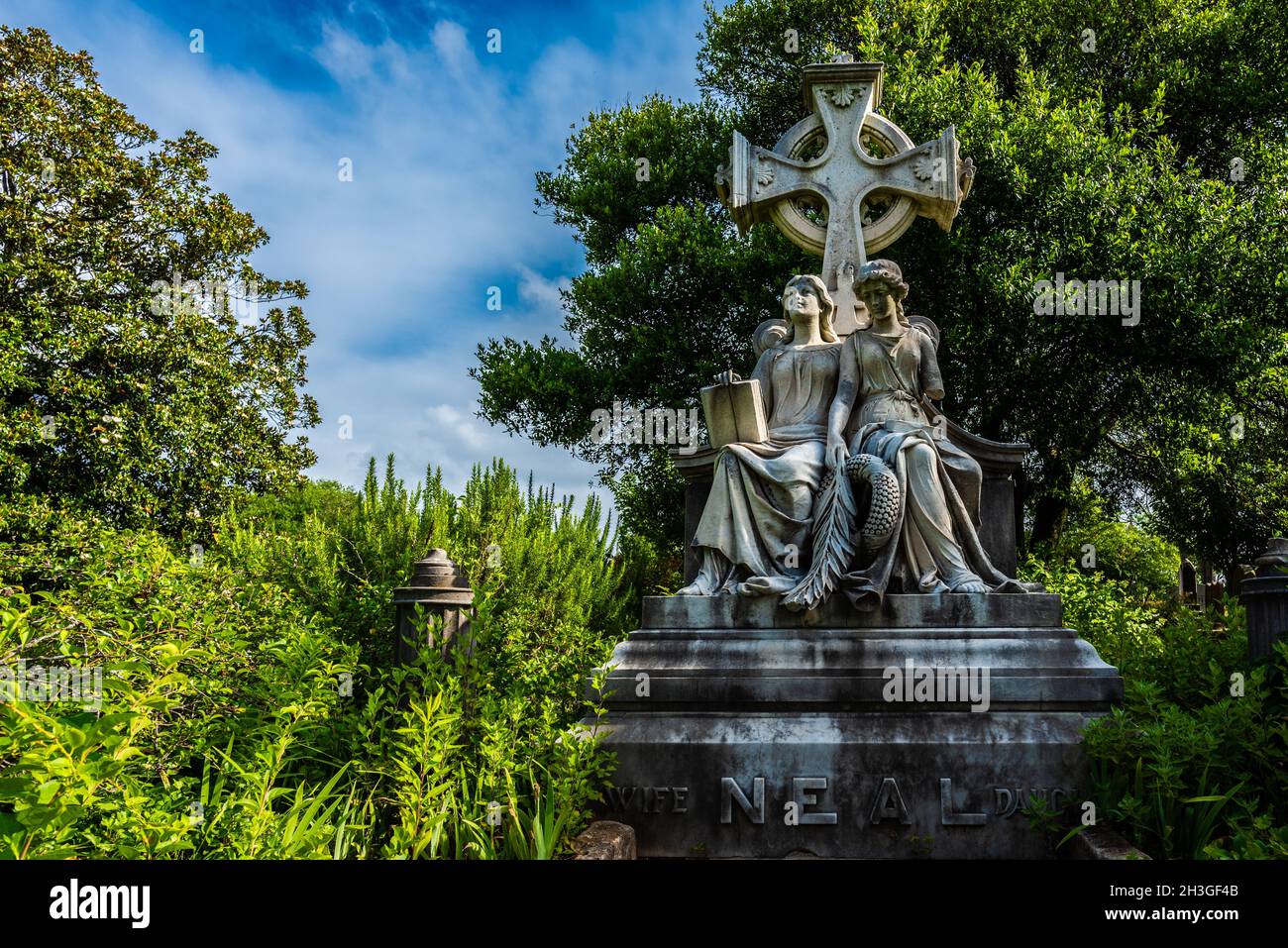 Big gravestone in the shape of a cross with sculptures of two girls in ...