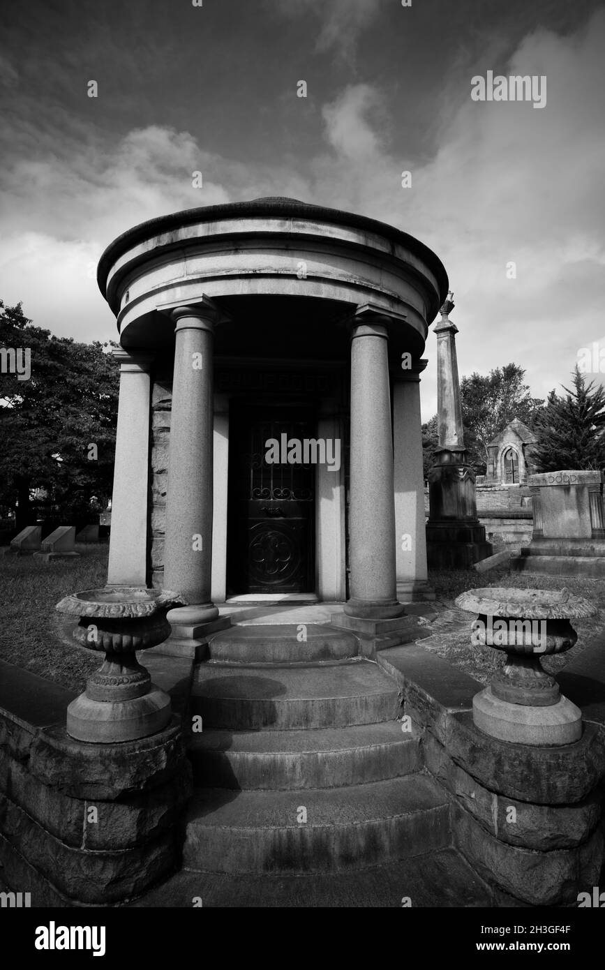 Grayscale shot of a tomb in the cemetery with round-shaped entrance ...