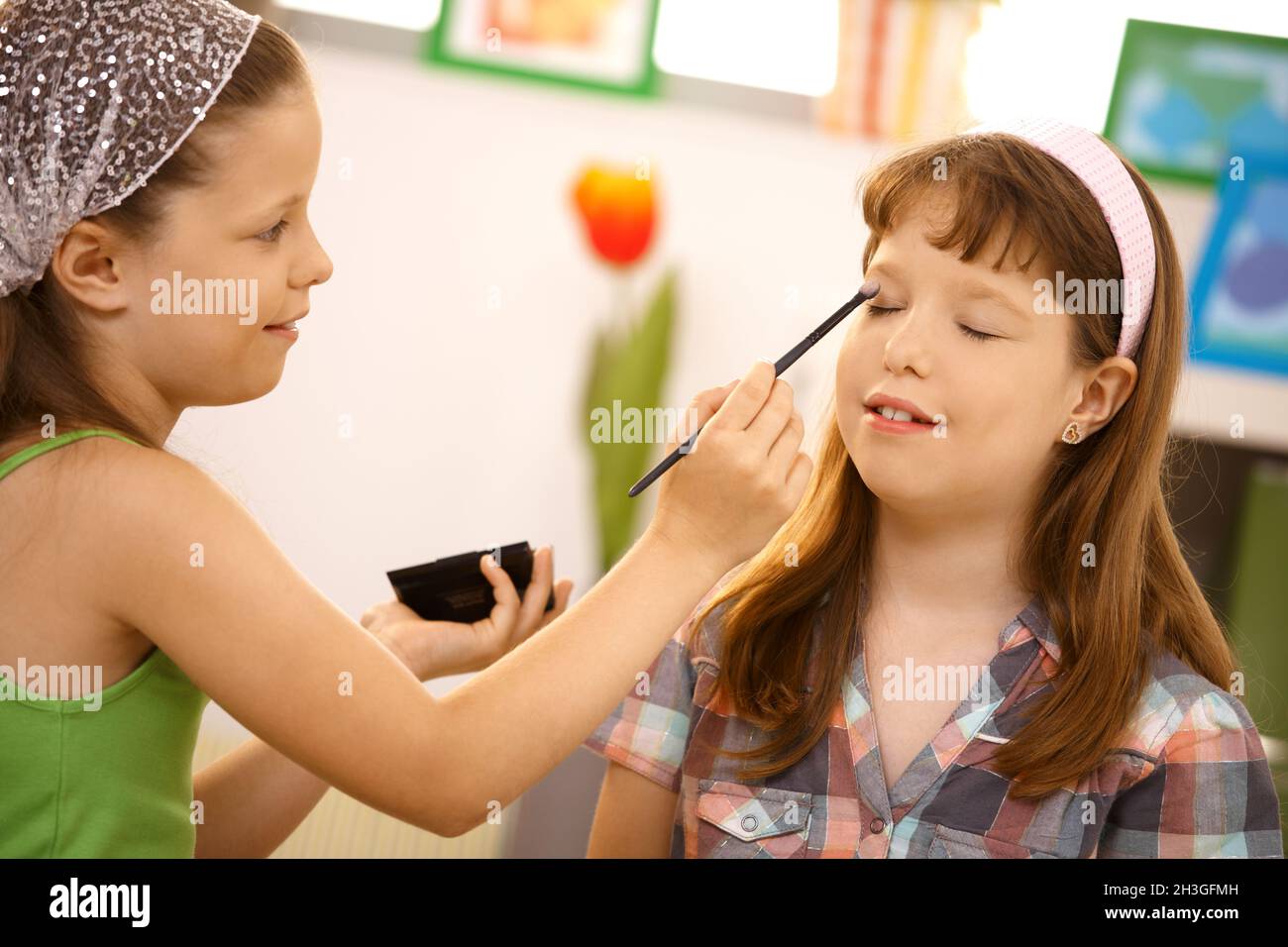 Young girl putting makeup on friend Stock Photo - Alamy