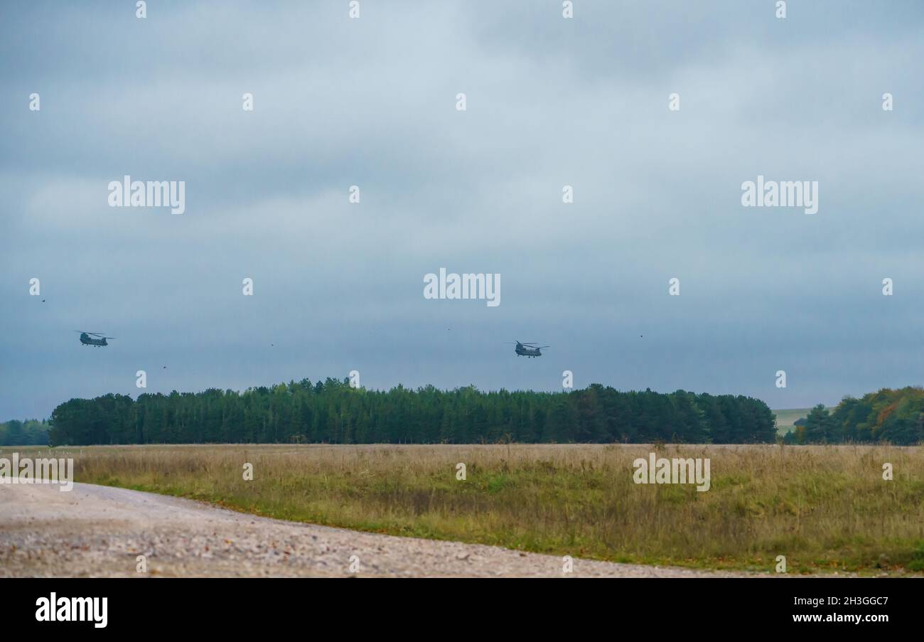 Two RAF Chinook CH-47 HC6A helicopters flying low in a cloudy blue grey ...