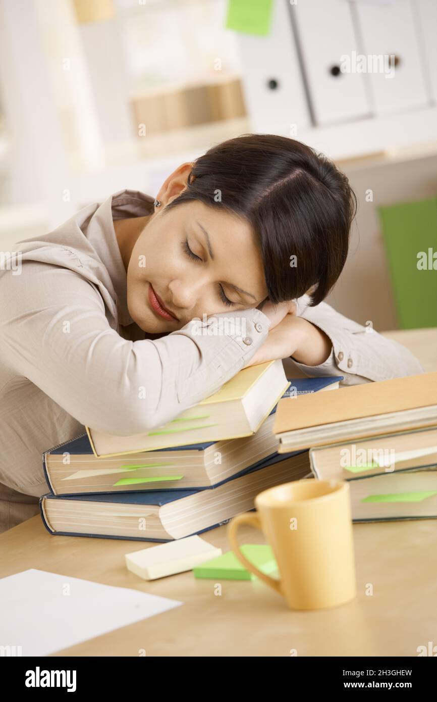 Tired student resting on pile of books Stock Photo - Alamy