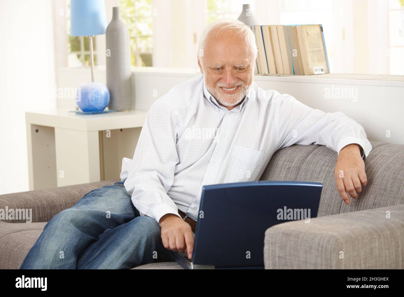 Older man smiling at computer screen at home Stock Photo - Alamy