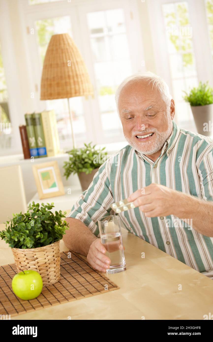 Smiling old man taking medication Stock Photo - Alamy