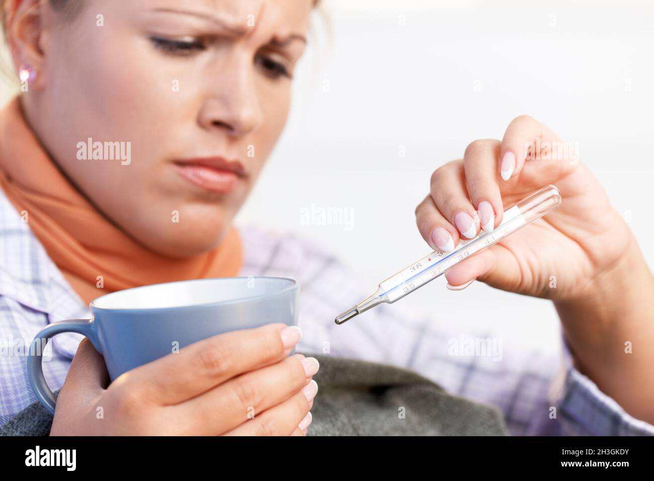 Young female having flu taking her temperature Stock Photo - Alamy