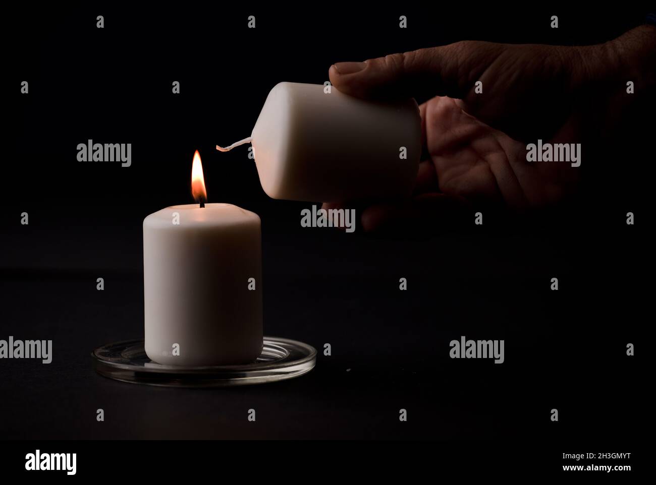 burning candle with flame, man's hands lighting candle, black ...