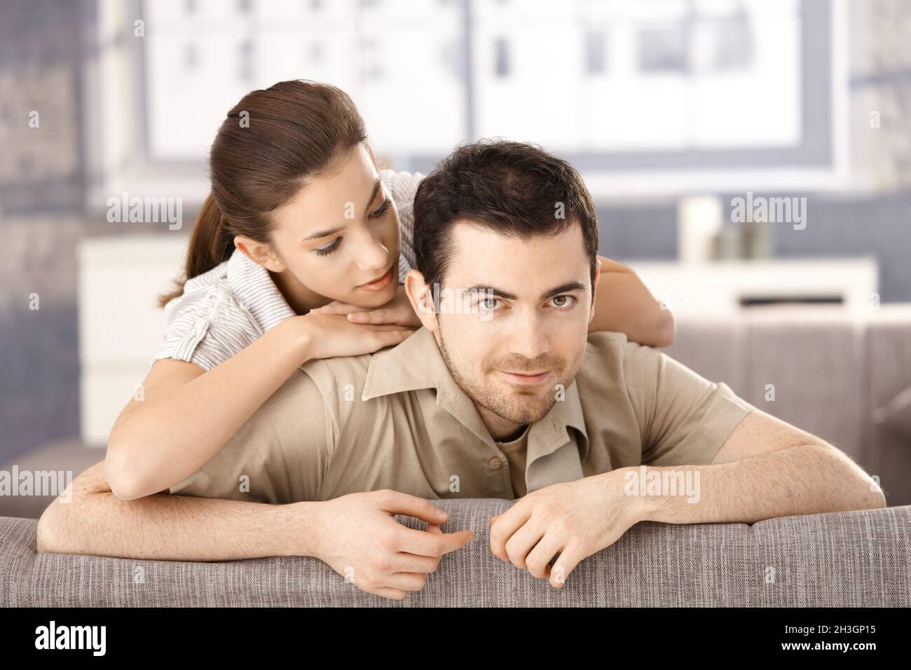 Happy couple sitting on sofa hugging each other Stock Photo - Alamy