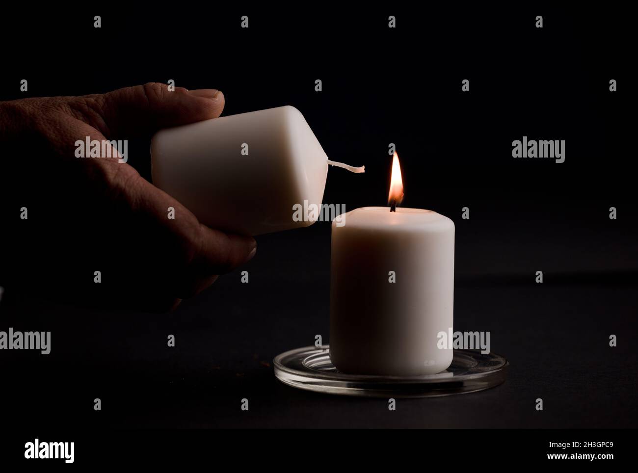 burning candle with flame, man's hands lighting candle, black ...