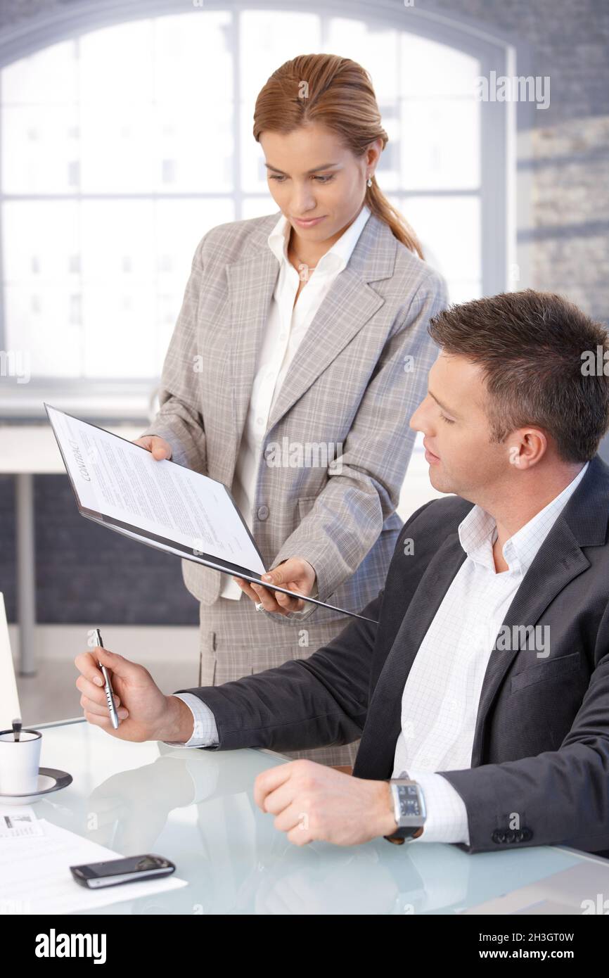 Secretary bringing contract to sign to boss Stock Photo - Alamy