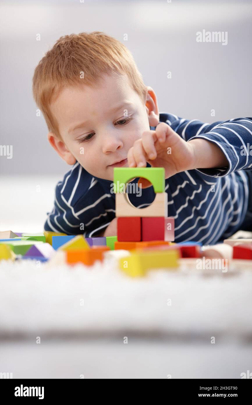 Sweet gingerish boy building tower at home Stock Photo - Alamy