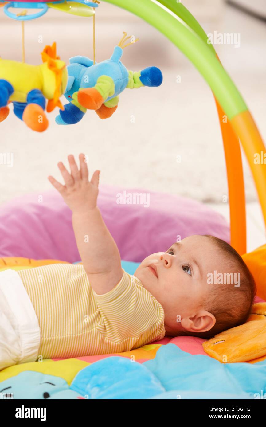 Baby reaching for toy Stock Photo - Alamy