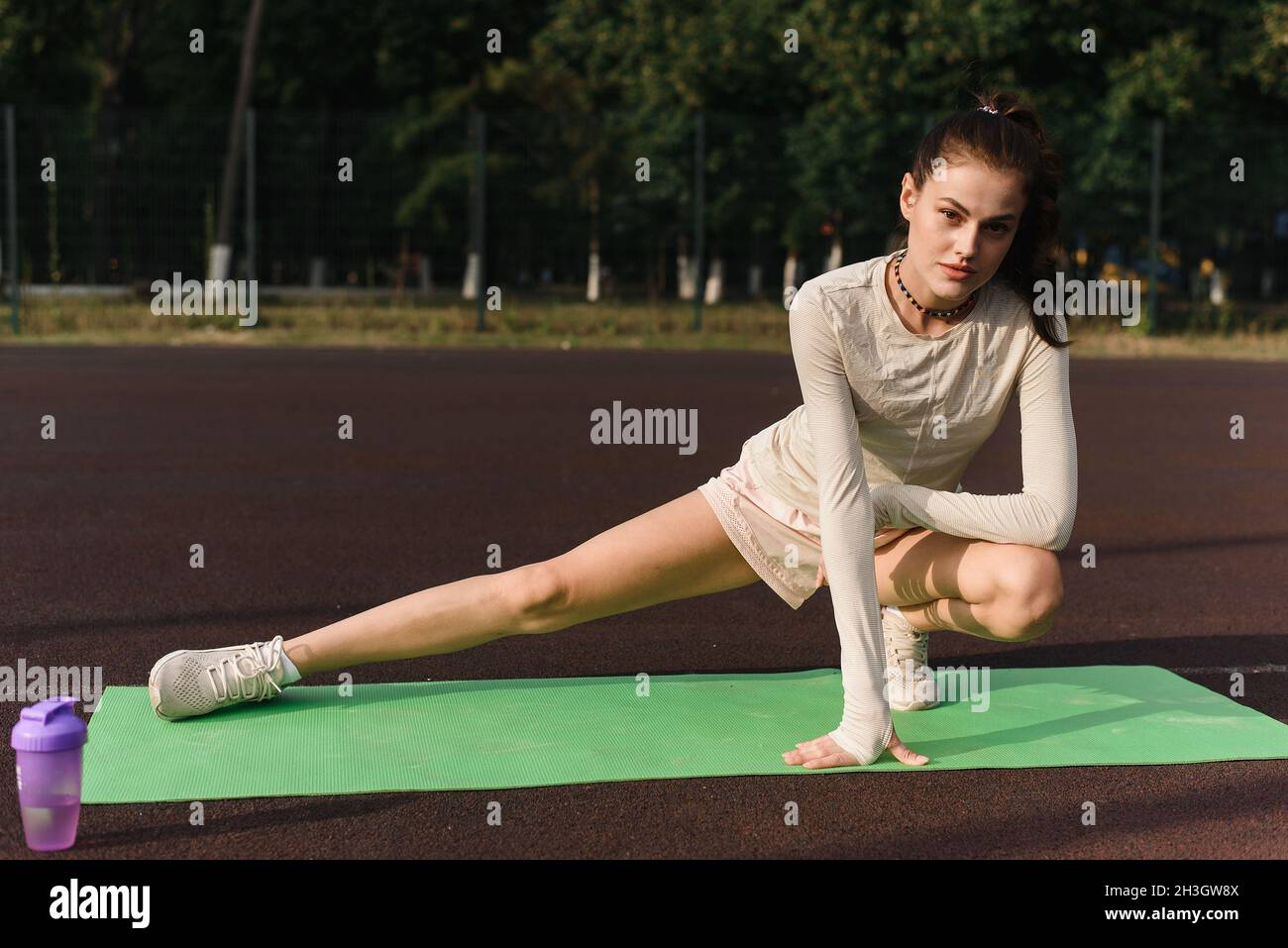 Sporty female beautiful model goes in for sports outdoors and looks at ...
