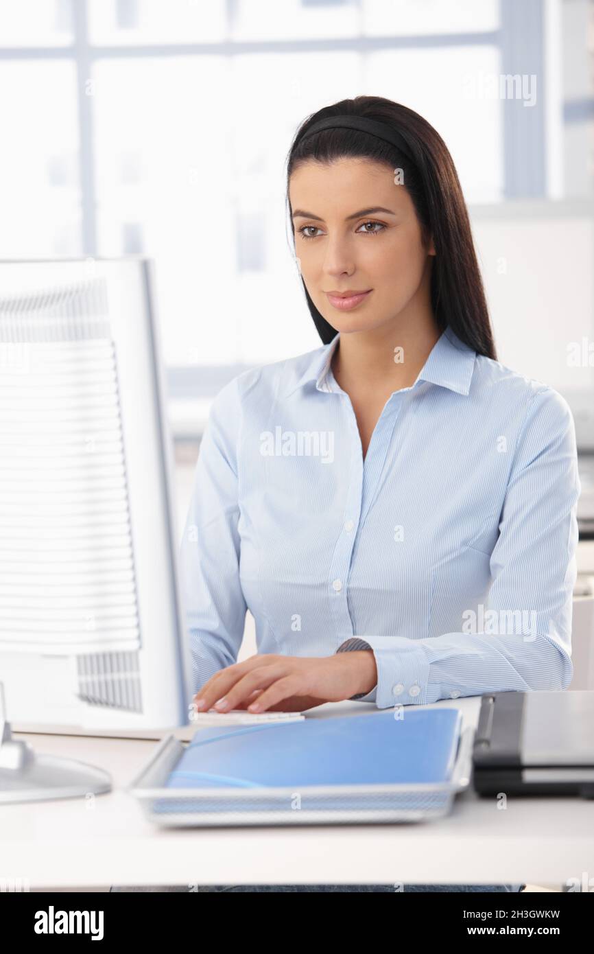 Pretty office worker at desk Stock Photo - Alamy