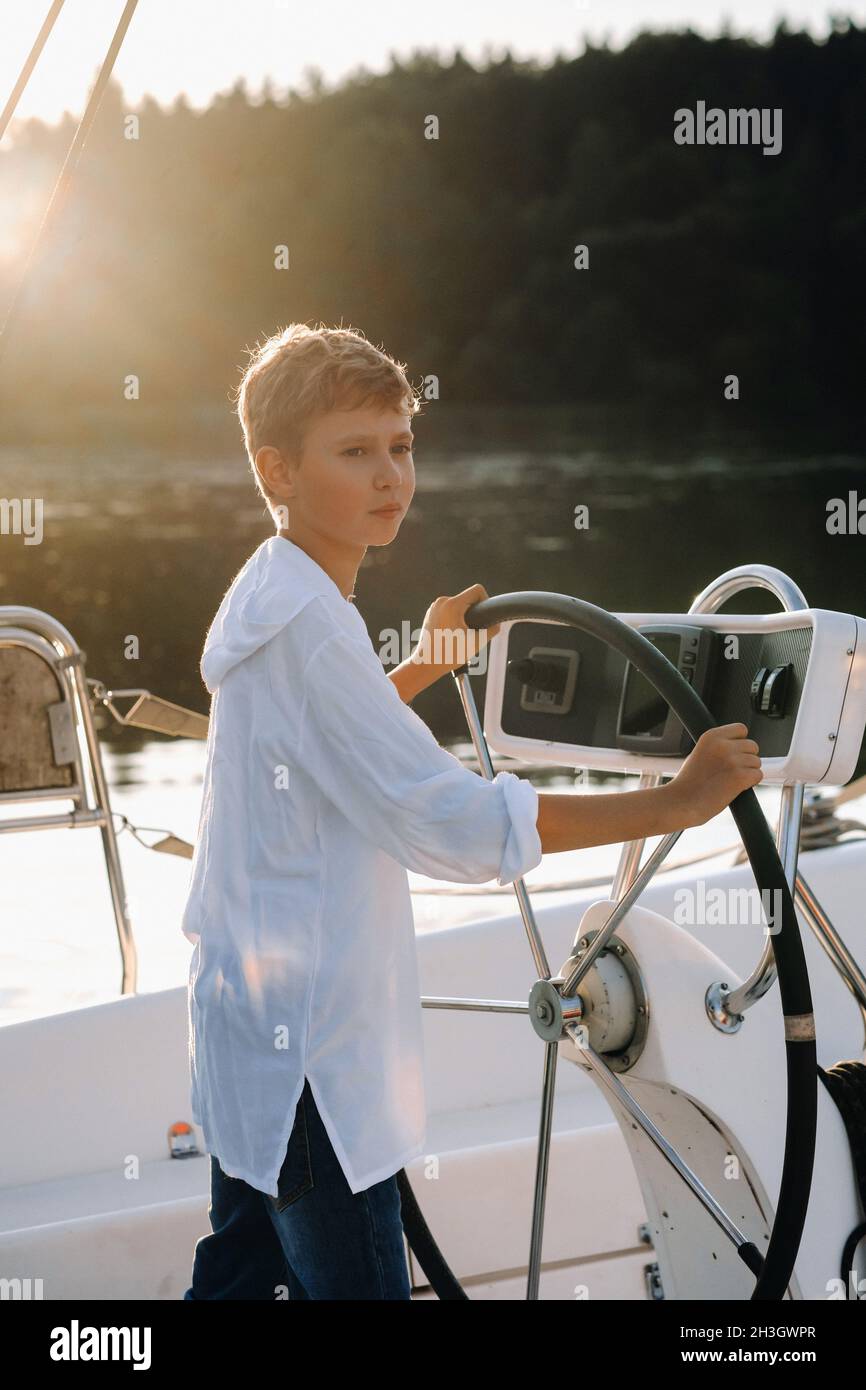 a little captain at the helm on a yacht. a little boy at the helm of ...