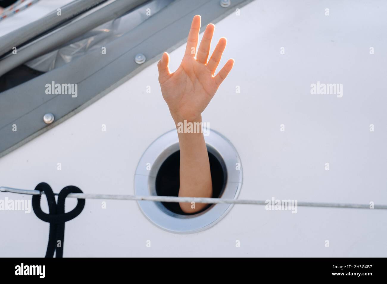 A man's hand sticks out of the porthole window on a ship at sea Stock ...