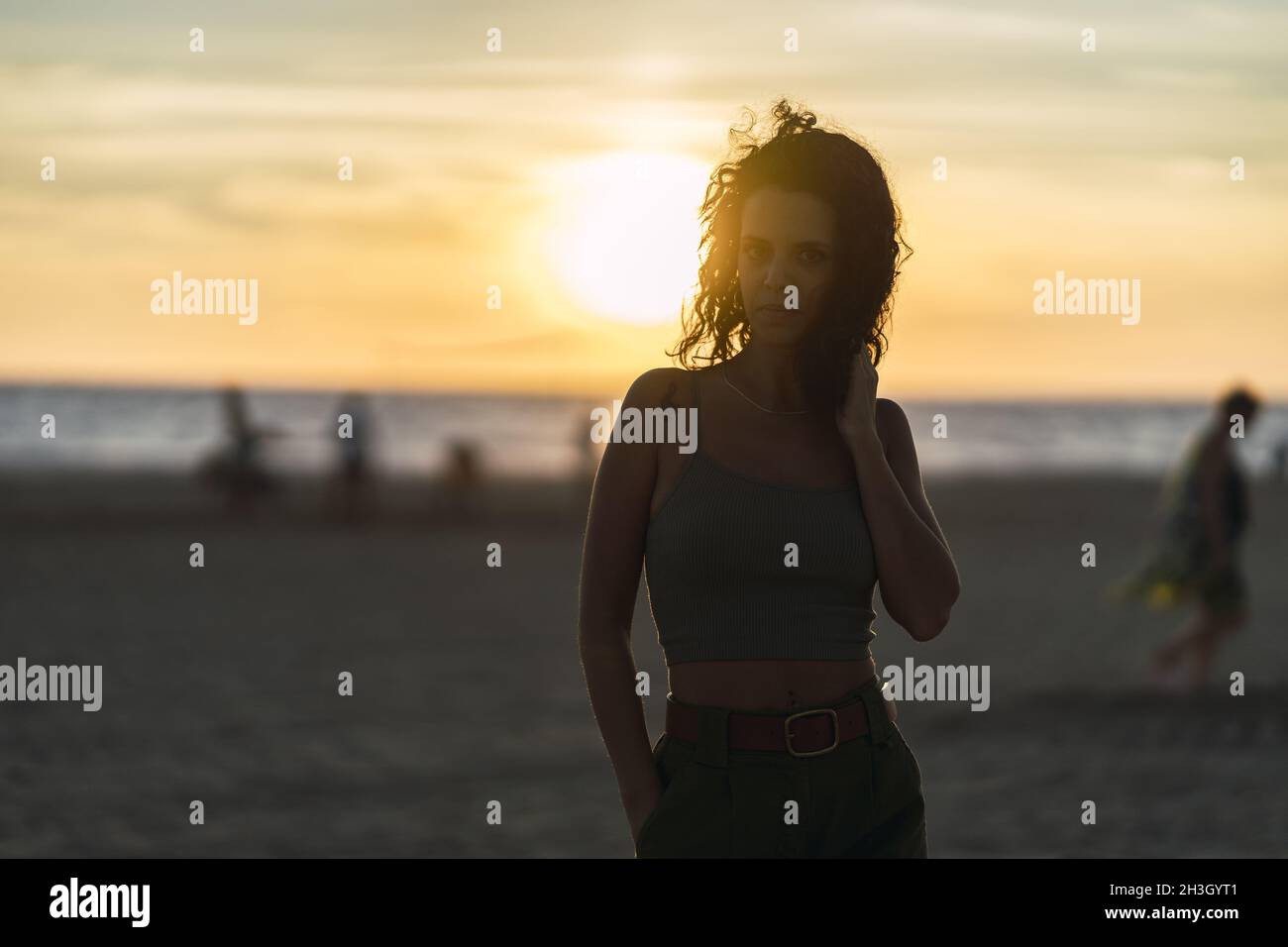 Spanish curly female posing on the sand at sunset Stock Photo - Alamy
