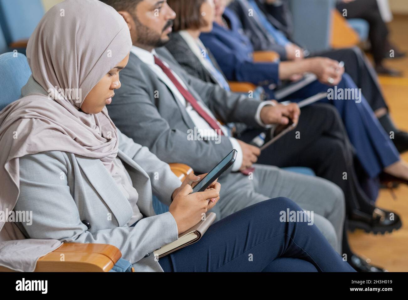 Concentrated Muslim nusinesswoman in hijab using smartphone while ...
