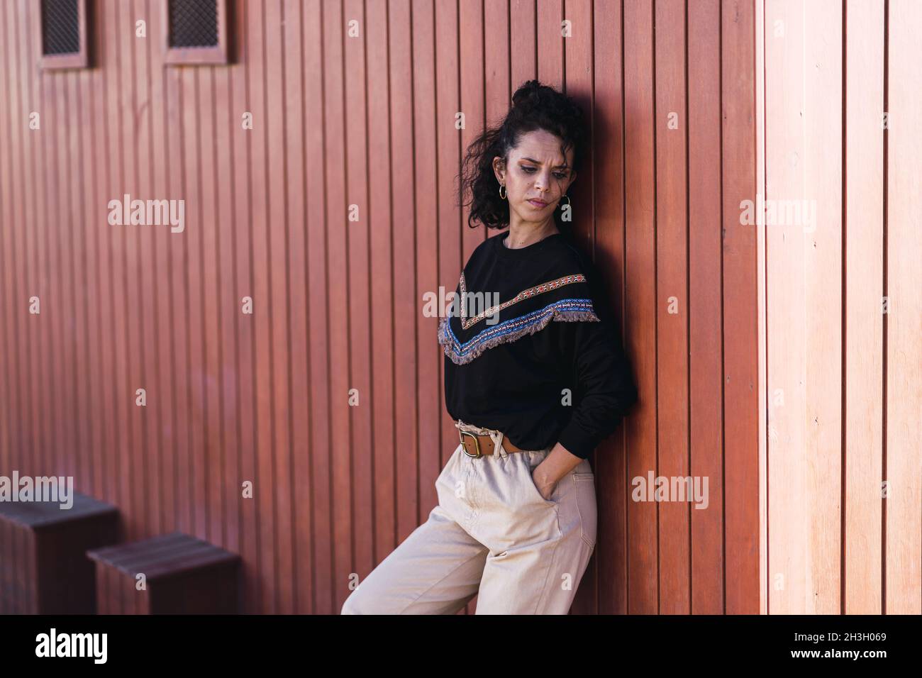Spanish curly female posing near the wall Stock Photo - Alamy