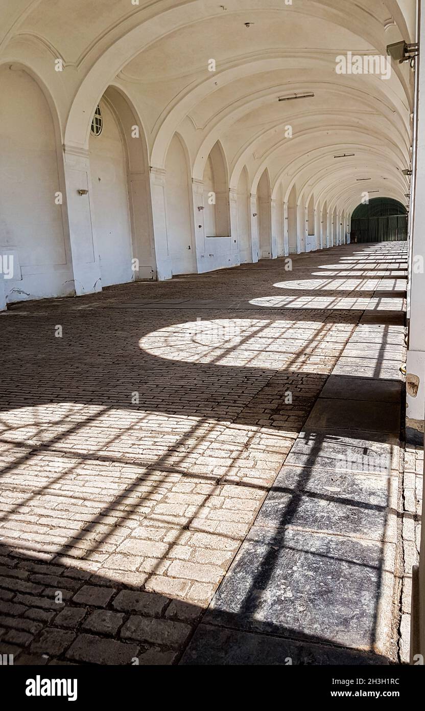 Long corridor through archway with repeating shadow patterns in ...