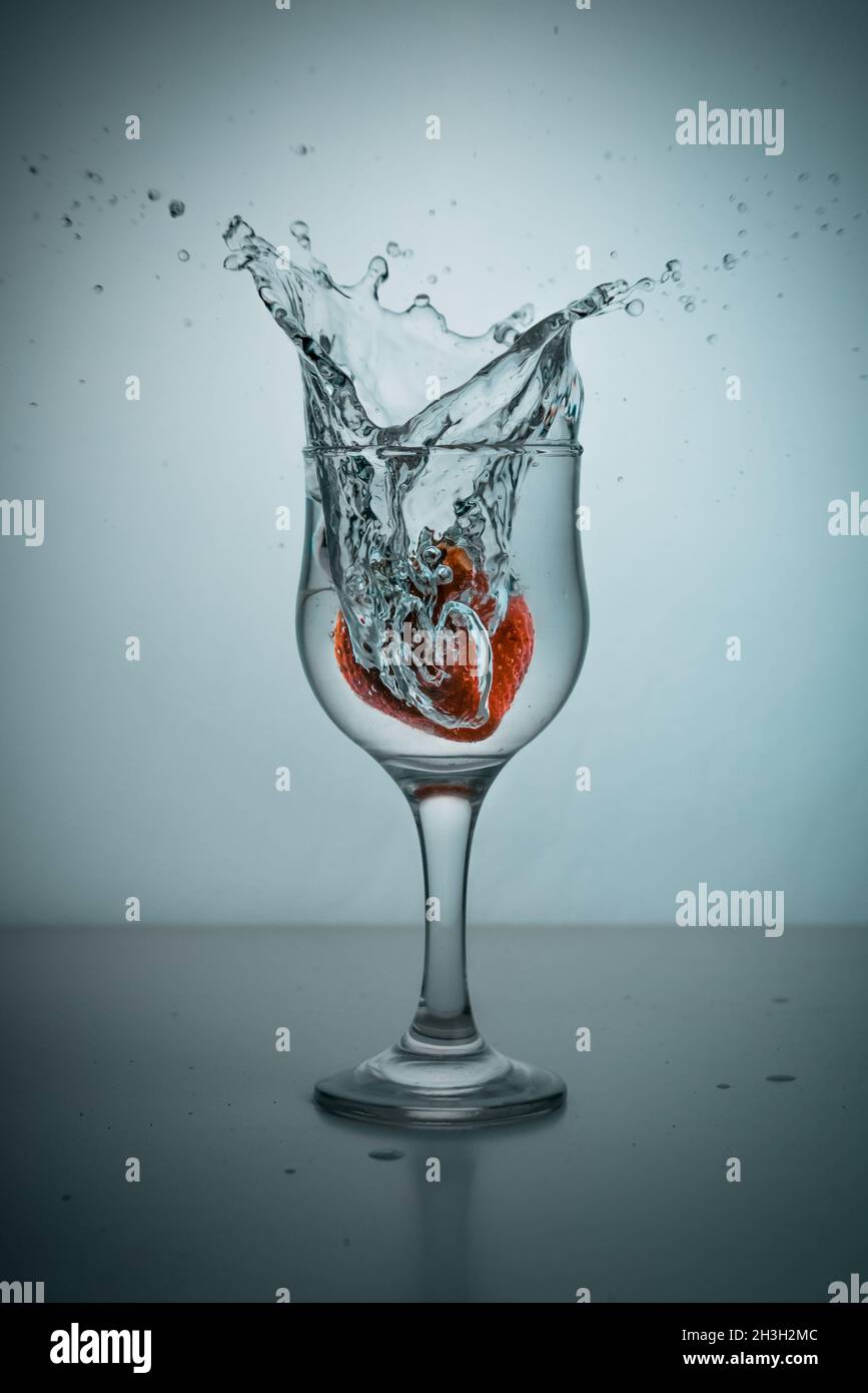 A strawberry dropped into a glass of water Stock Photo - Alamy