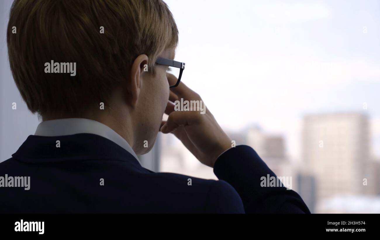 Close-up businessman looking out window. Young manager with thoughtful ...