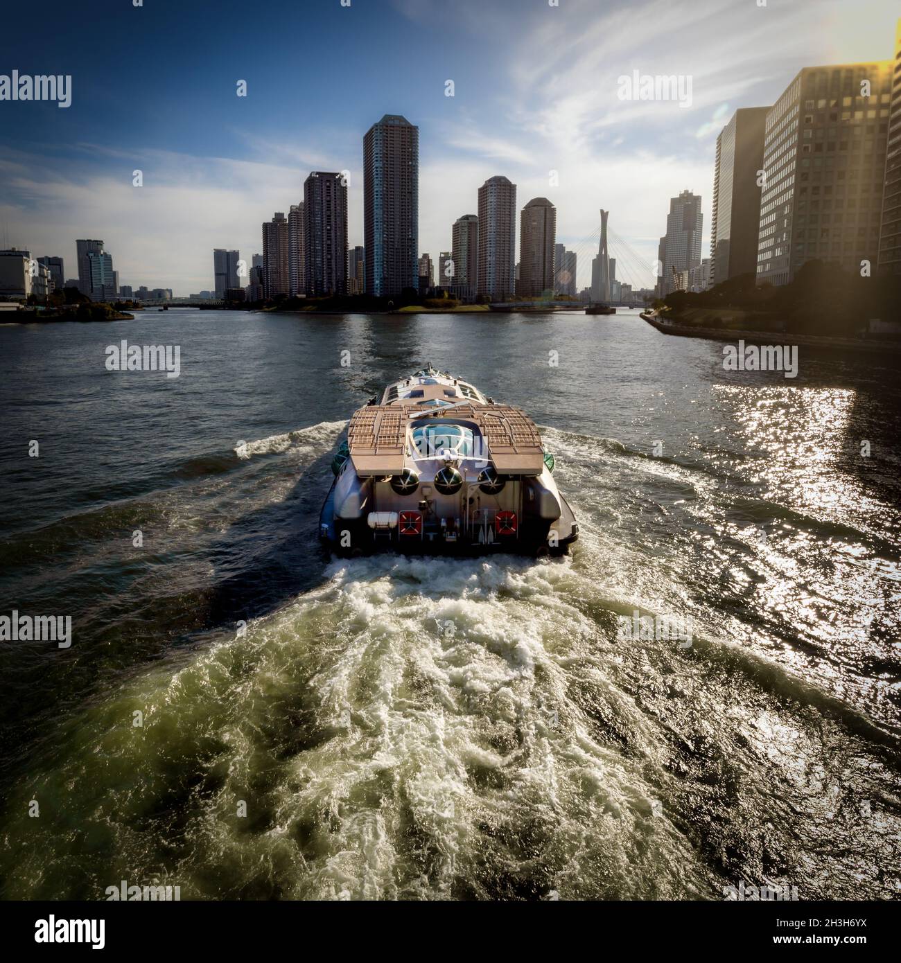 The wake of a riverboat cruising up the Sumida River toward the Tsukuda ...