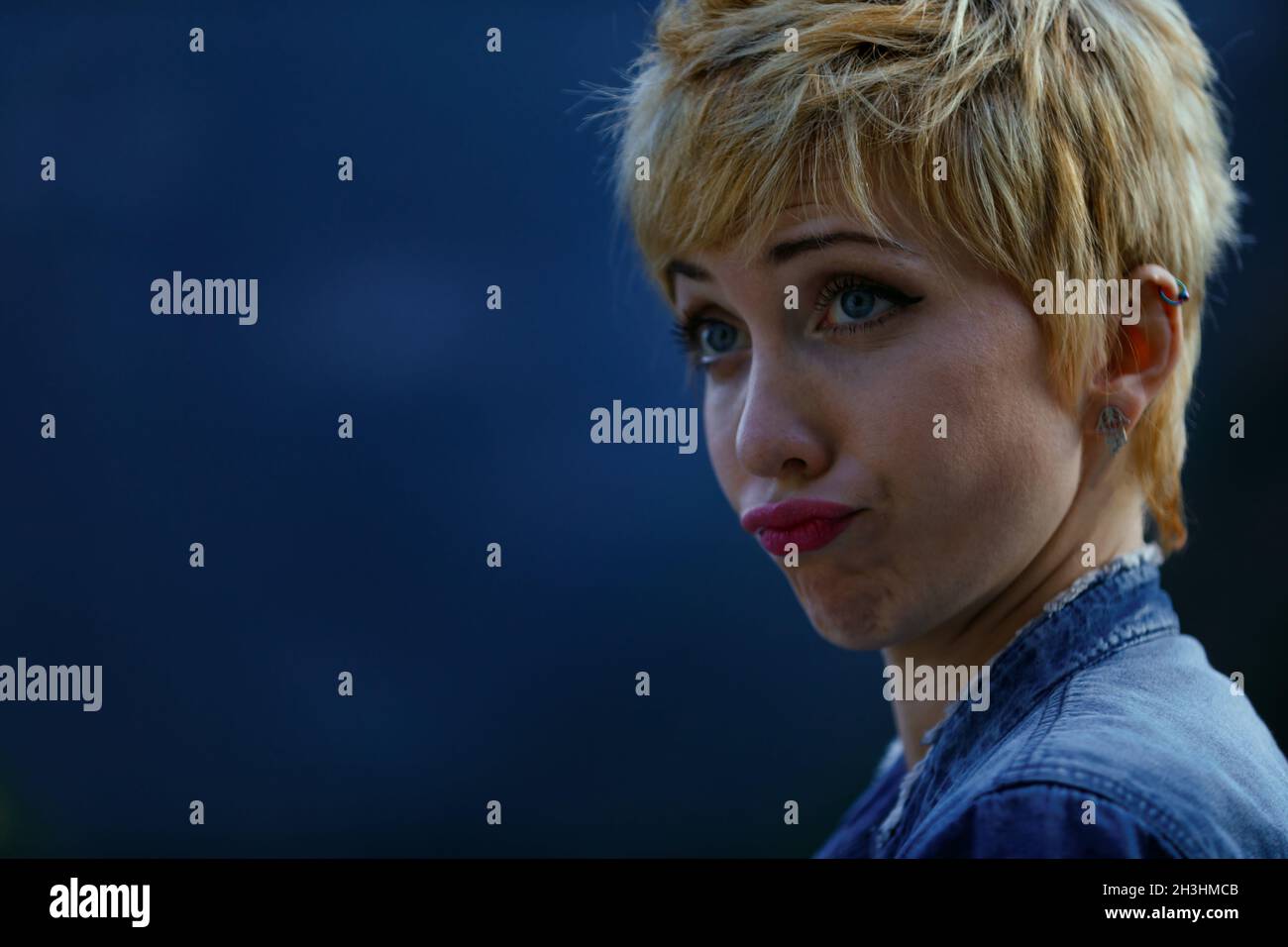 girl makes a funny face by puffing up her cheeks and puckering her lips ...